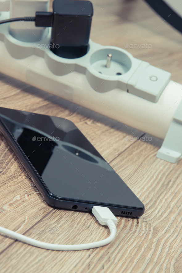 Smartphone and chargers connected to electrical power strip. Various ...