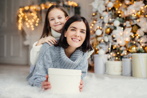 Indoor shot of mother and daughter have fun together, share presents ...