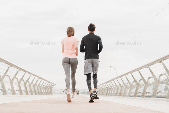 Young fit friends couple boyfriend and girlfriend athletes jogging ...