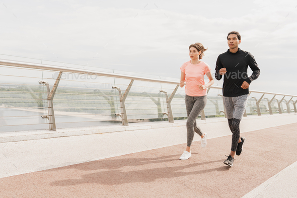 Fit young romantic couple athletes man and woman jogging running ...