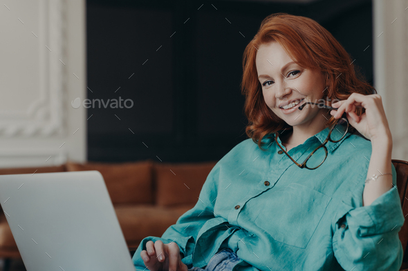 Positive good looking young woman freelancer works remotely on laptop ...
