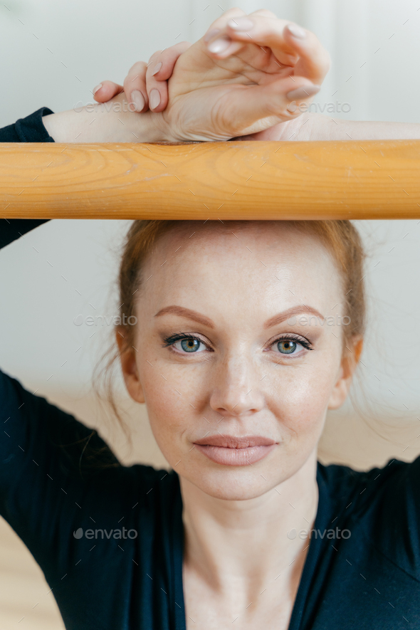 Headshot of talented skilled female ballet dancer poses near barre, has ...