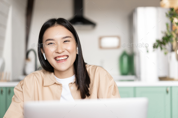 Happy asian girl laughing, working on laptop from home. Young woman ...