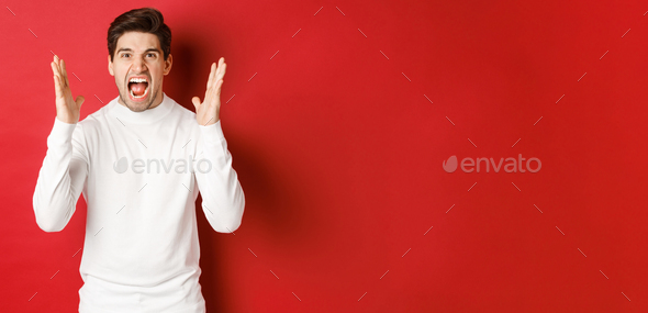 Image of frustrated and angry man in white sweater, shouting in rage ...