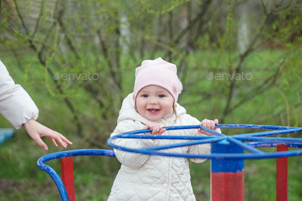 Smiling baby toddler rides carousel in playground outside. Concept of ...