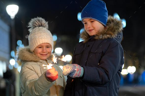 Two cute young children, boy and girl in warm winter clothing holding ...