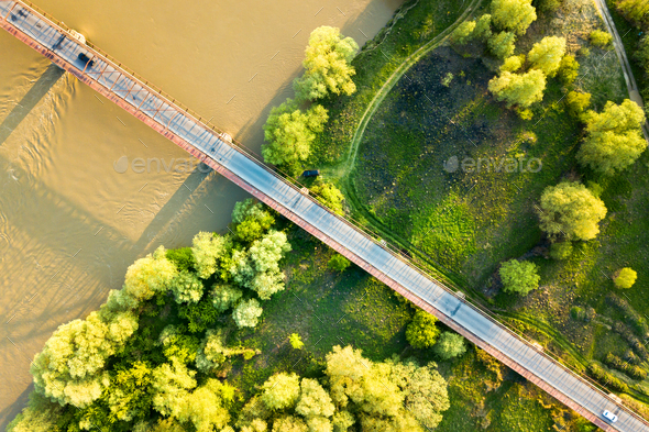 Aerial view of a narrow road bridge stretching over muddy wide river in ...