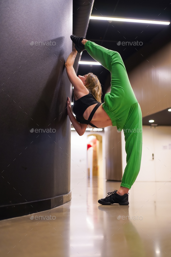 An urban and classical dancer woman inside a building, lifting her leg ...