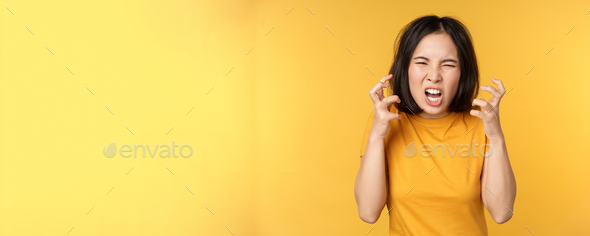 Image of angry asian woman, shouting and cursing, looking outraged ...