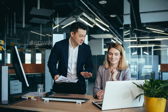 two business people consulting on a project looking at computer monitor ...
