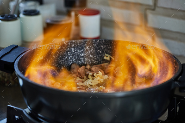 Beef meat fried with onions in frying pan, flambe on gas stove Stock ...