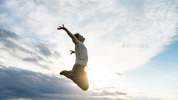 Excited young man jumping high up in the air Stock Photo by Gajus-Images
