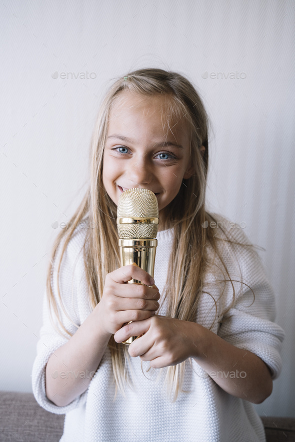 beautiful little girl singing with microphone Stock Photo by karrastock