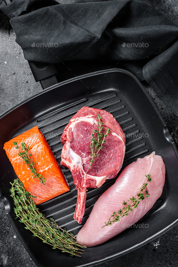 Cooking raw steaks. Fish salmon fillet, beef meat and turkey breast on ...