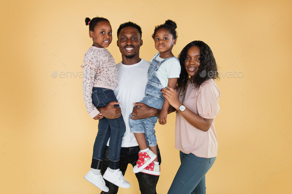 Happy african parents and two daughters embracing each other standing ...