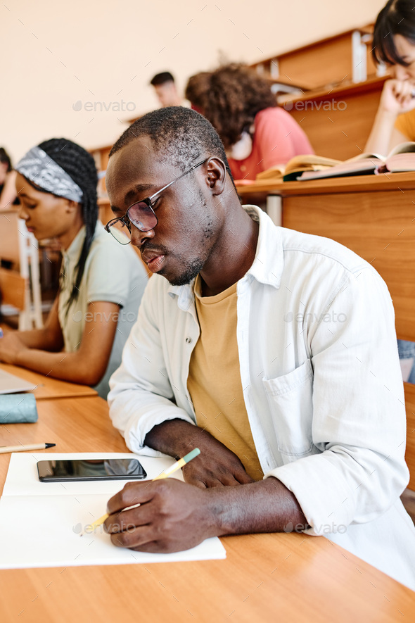 Student writing exam at auditorium of university Stock Photo by AnnaStills