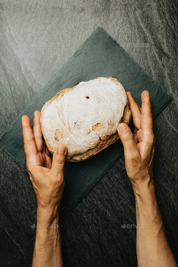 Old hands preparing freshly baked artisan and organic bread over a ...