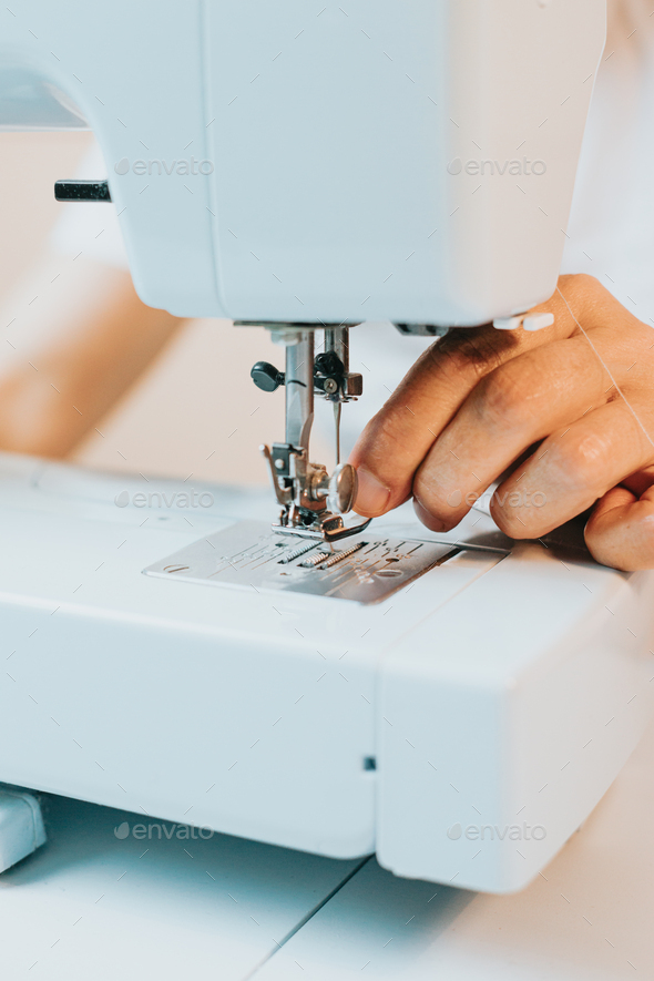 Old woman tailor working on sewing machine smiling happy to camera ...