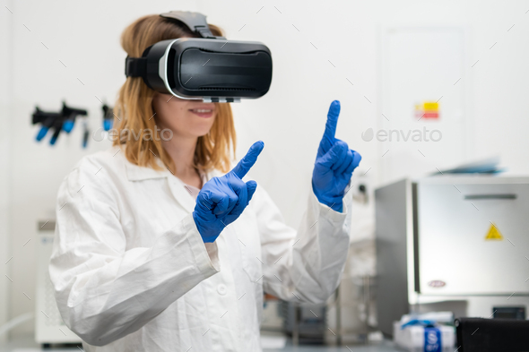 Scientist in VR googles, lab coat and rubber gloves manages the virtual ...