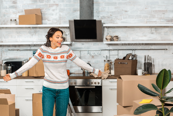 laughing young woman doing shrug gesture in kitchen with cardboard ...