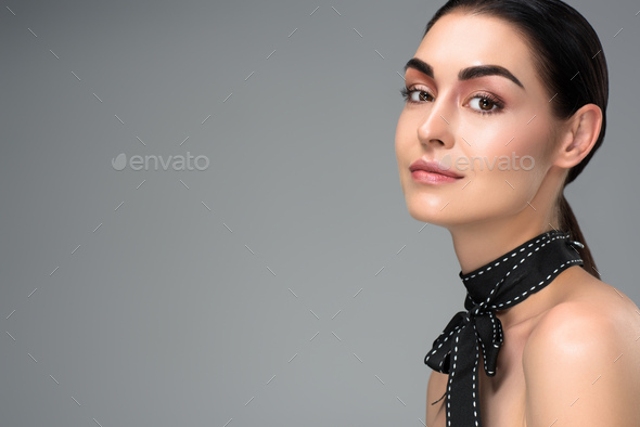 side view of beautiful brunette girl with black bow on neck smiling at ...