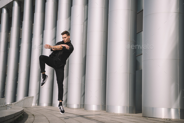 handsome young man in black clothes dancing near columns Stock Photo by ...