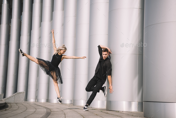 beautiful young couple of dancers in black clothes dancing near columns ...