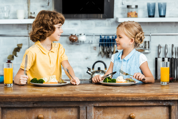 cute happy children eating healthy vegetables and smiling each other ...