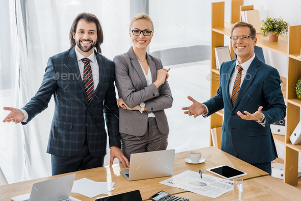 smiling insurance agents standing near table in office Stock Photo by ...