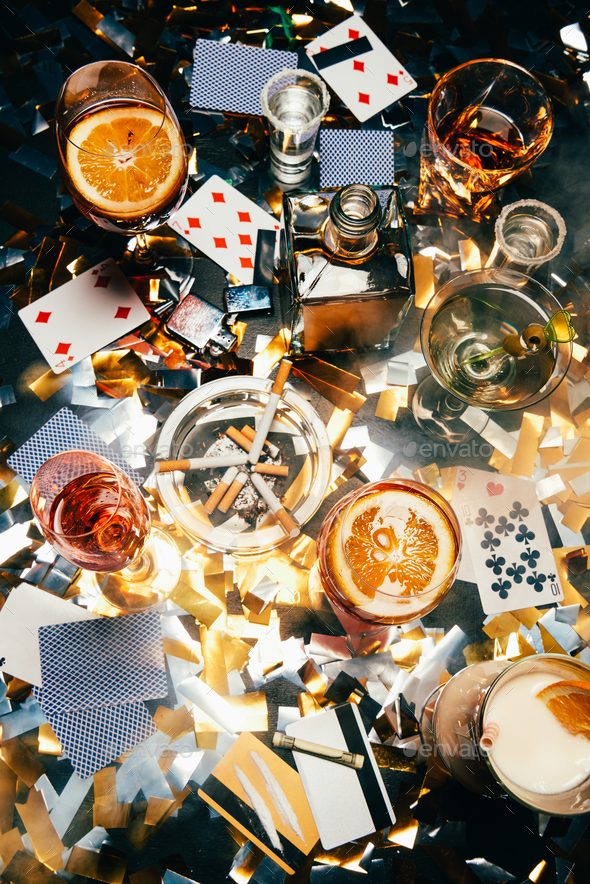 top view of cigarettes, alcoholic cocktails, playing cards, rolled ...