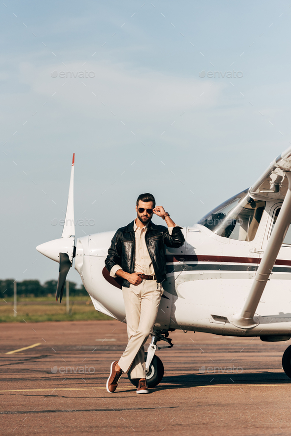 stylish male pilot in leather jacket and sunglasses posing near ...