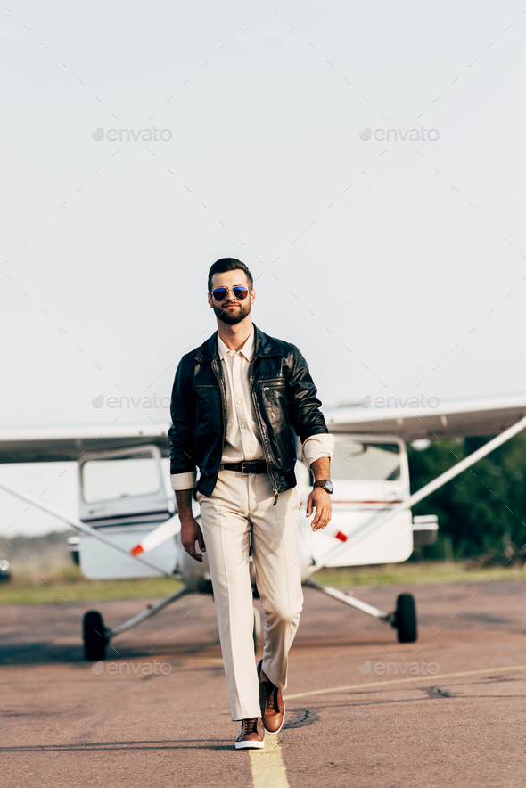 handsome male pilot in leather jacket and sunglasses walking near ...