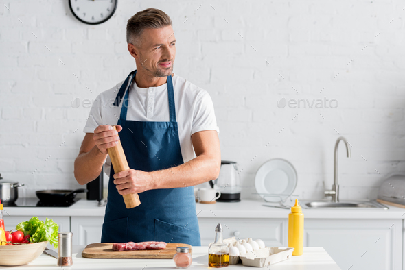 Smiling man enjoying cooking dinner in kitchen Stock Photo by ...