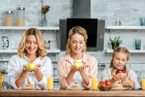 three generations of women with pancakes and healthy apples for ...