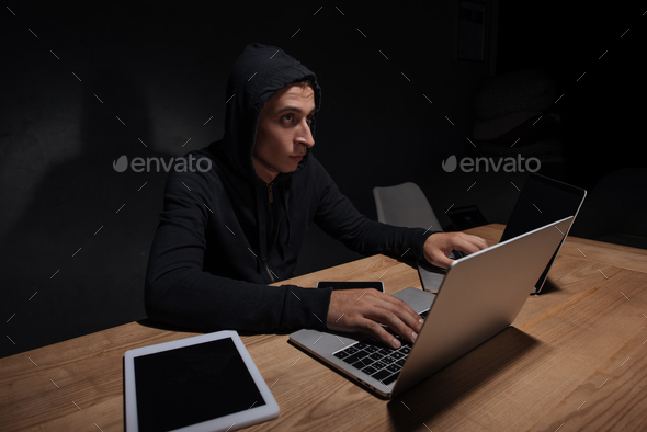 hacker in black hoodie using laptops in dark room, cyber security ...
