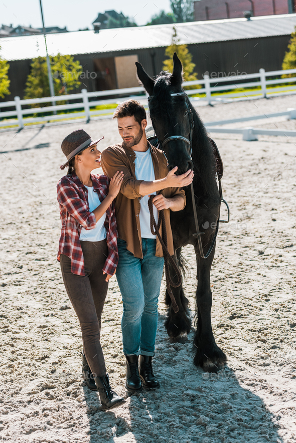 happy female and male equestrians walking with horse at ranch Stock ...