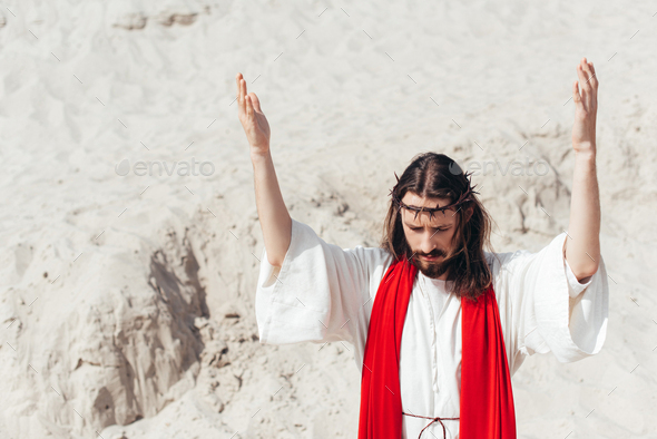 Jesus standing with raised hands and praying in desert Stock Photo by ...