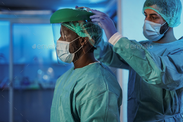 Multiracial male doctors preparing and getting dressed to work inside ...