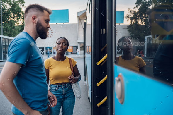 Multiracial friends waiting for a bus while at a bus stop Stock Photo ...