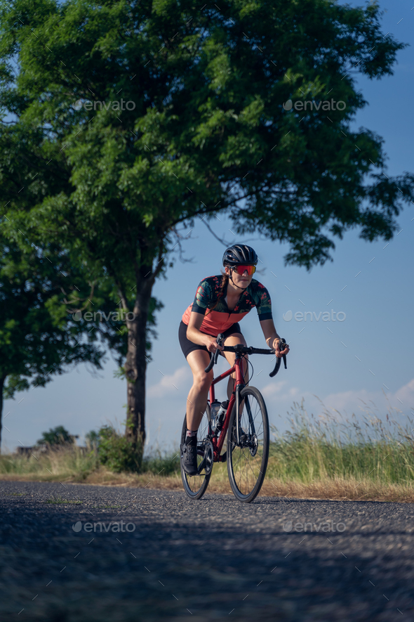 Vertical, Angle photo of a young woman, pedaling, riding speed a road ...