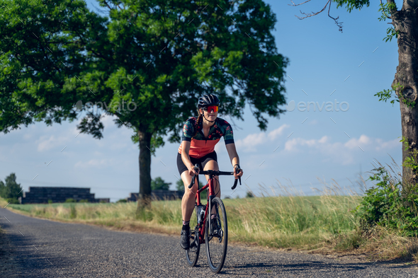 Angle photo of a young woman, pedaling, riding a road bike, on a ride ...