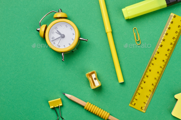 Yellow school supplies on green background. Stock Photo by stockfilmstudio