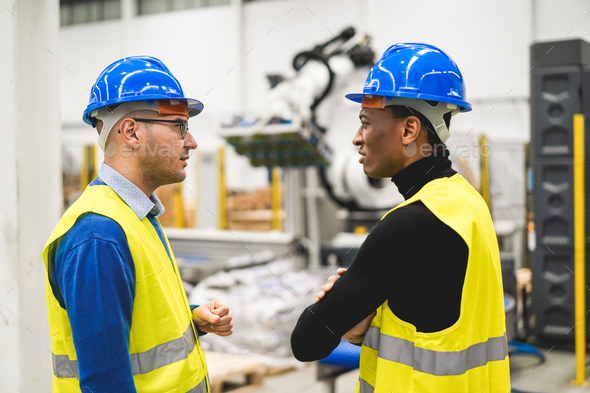 Multiethnic engineers working inside robotic factory - Focus on right ...