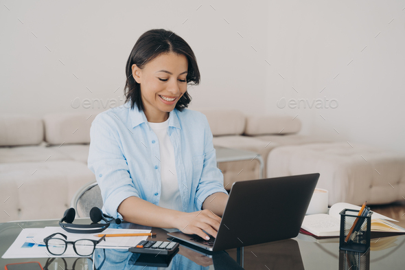 Happy woman is typing text on computer. Lady is chatting, having ...