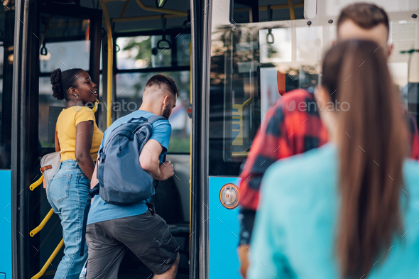 Multiracial friends entering a public transport at a bus stop Stock ...