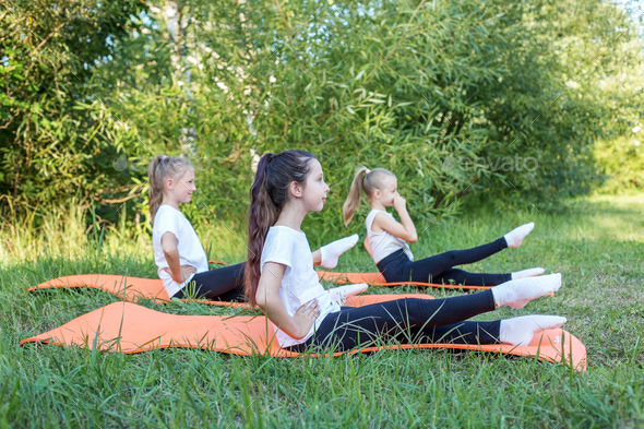 Children play sports in park using fitness mats. Training with ...
