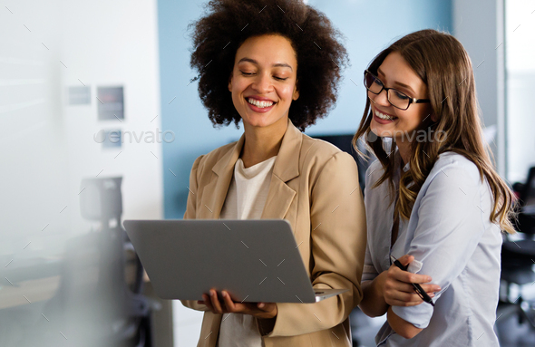 Happy multiethnic business women working together online on a laptop in corporate office. Stock ...