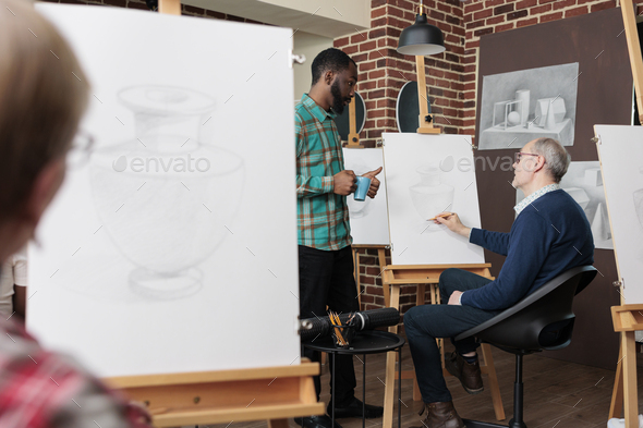 Young painting teacher explaining graphic technique to student Stock ...