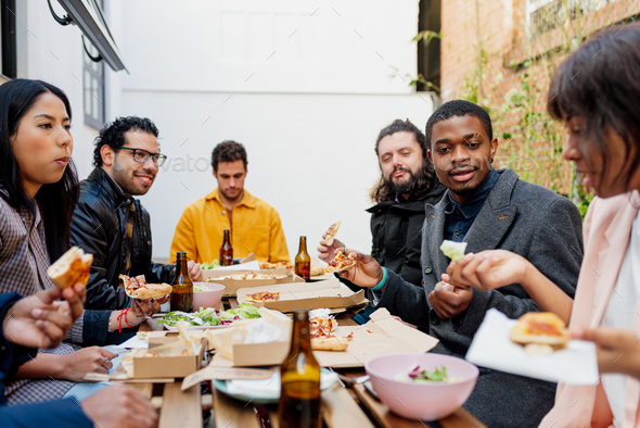 Group of multiracial friends celebrating with lunch at a restaurant ...