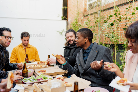 Group of multiracial friends celebrating with lunch at a restaurant ...